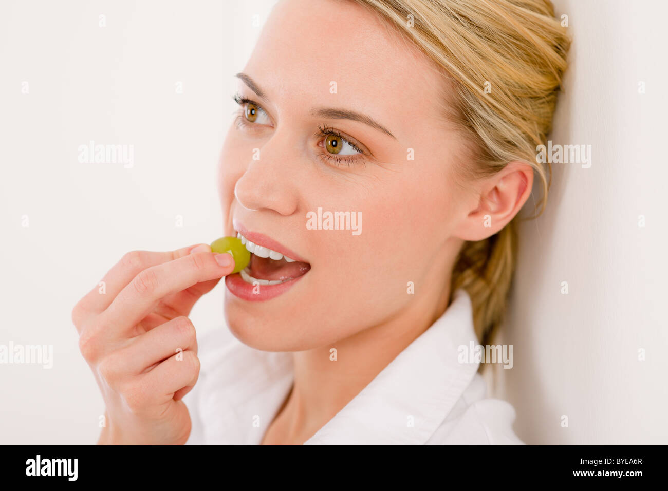 Healthy lifestyle - portrait of woman bite grape on white background ...