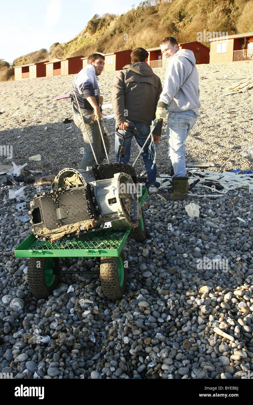 Men haul away car parts from a cargo container from the stricken ship ...