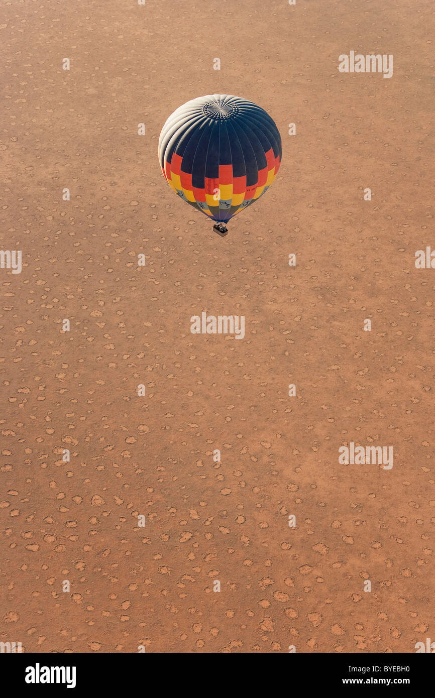A hot-air balloon above a sandy plain at the edge of the Namib Desert ...