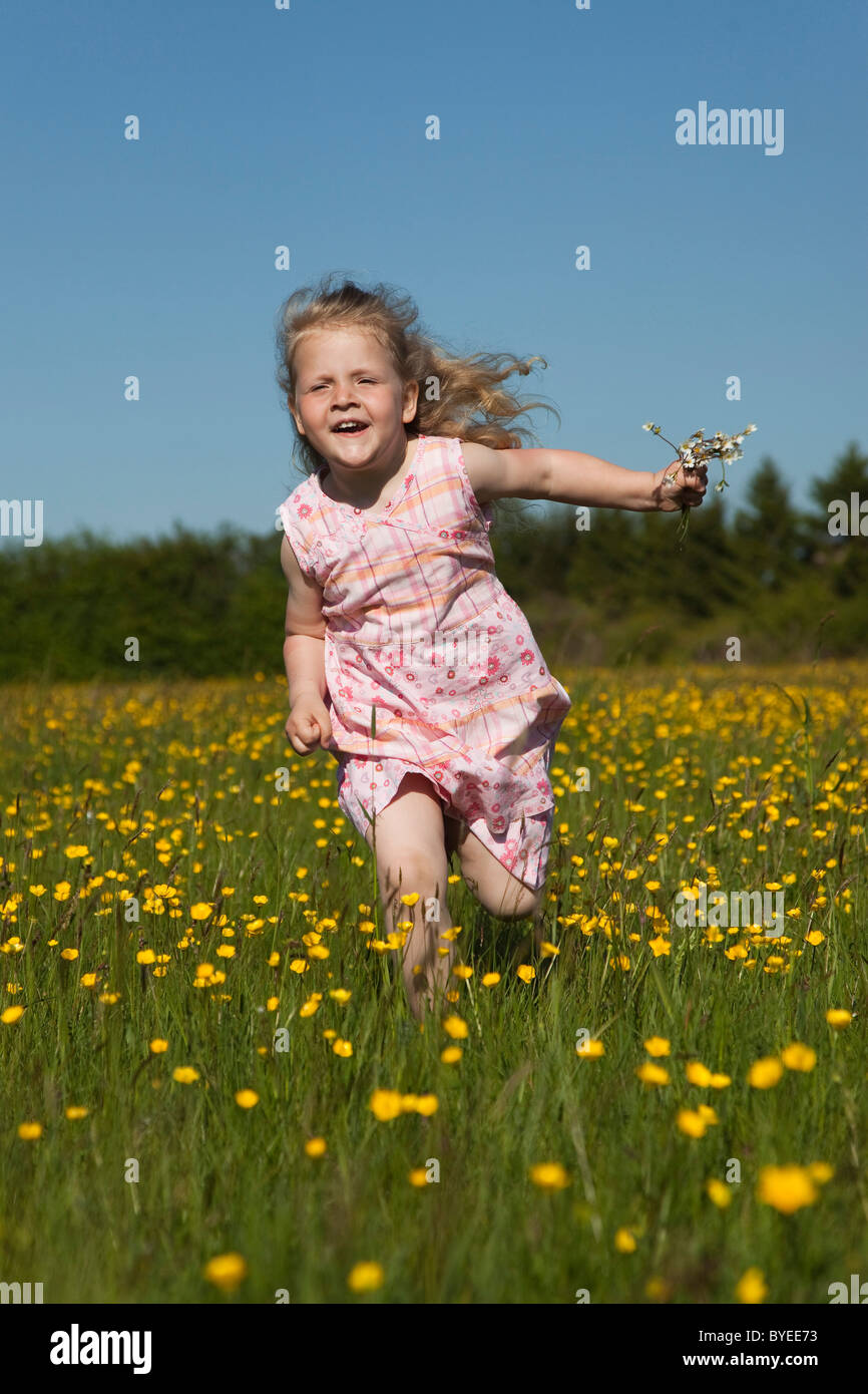 Girl, 4, while running across a meadow with flowers in her hand Stock ...