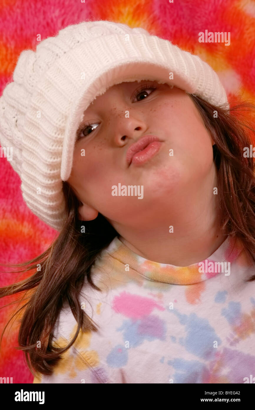 Young girl making a funny fishy or kissy face with knit hat and pink ...