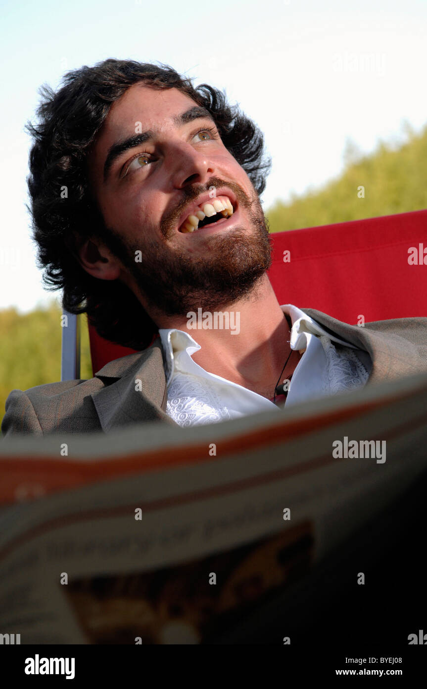 A happy young man smiling and laughing reading paper Stock Photo - Alamy