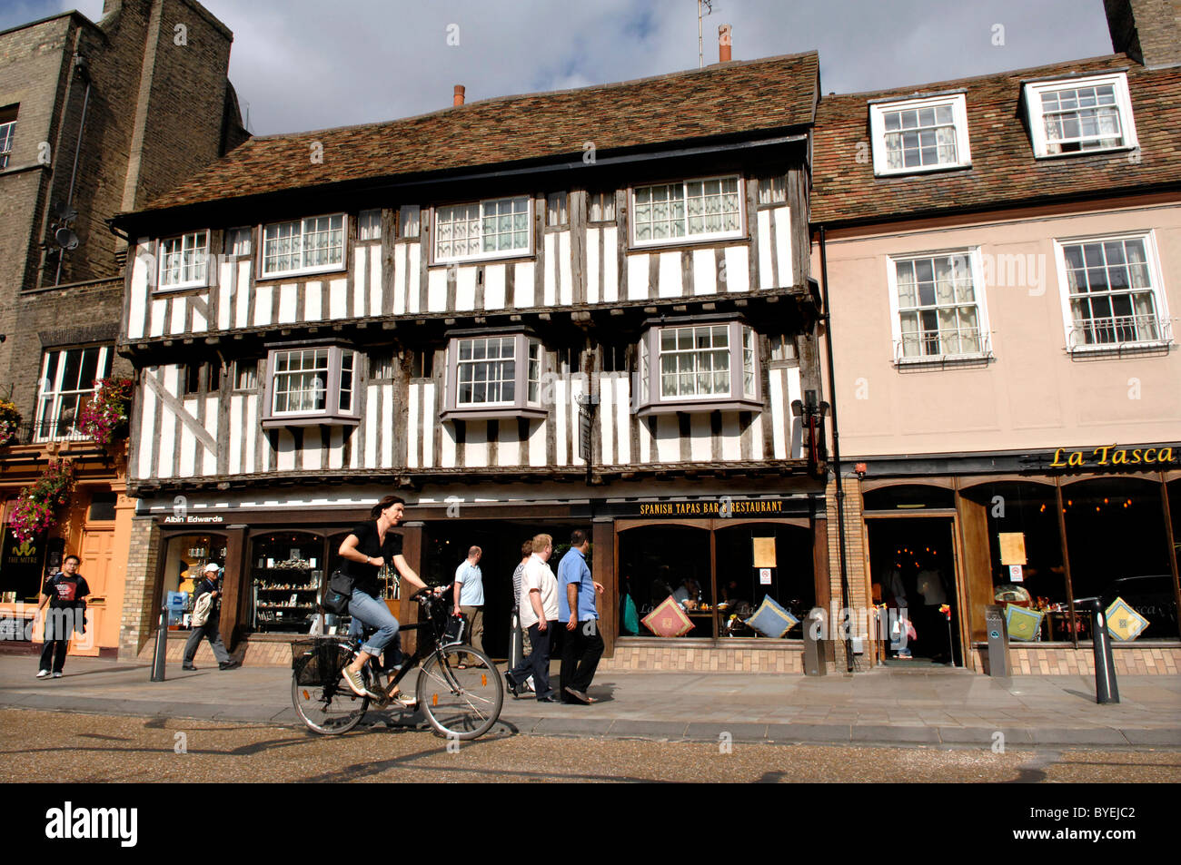 A cyclist passes an old wood timbered style building with shops in ...