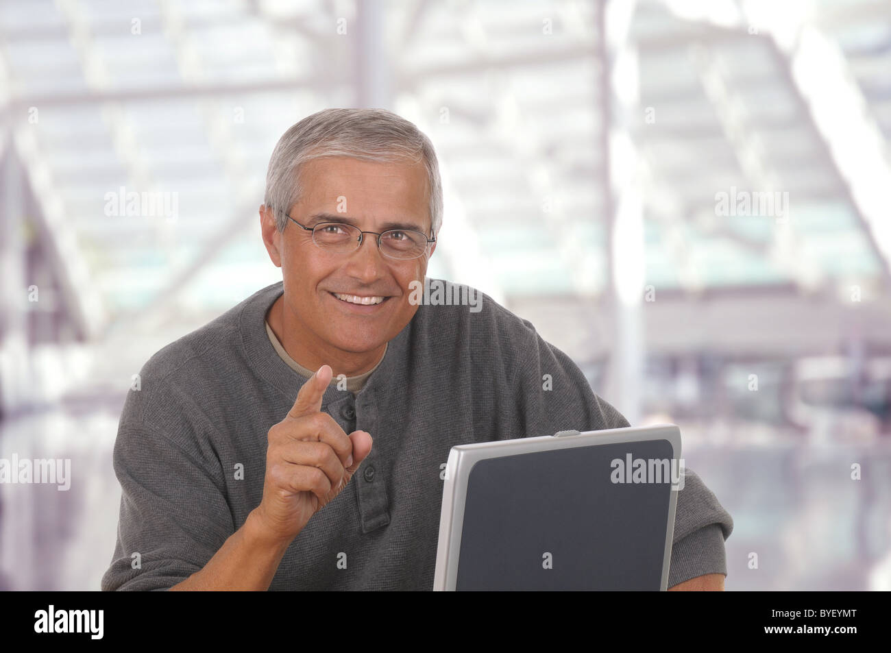 Middle aged man in lobby of modern office building laptop computer ...