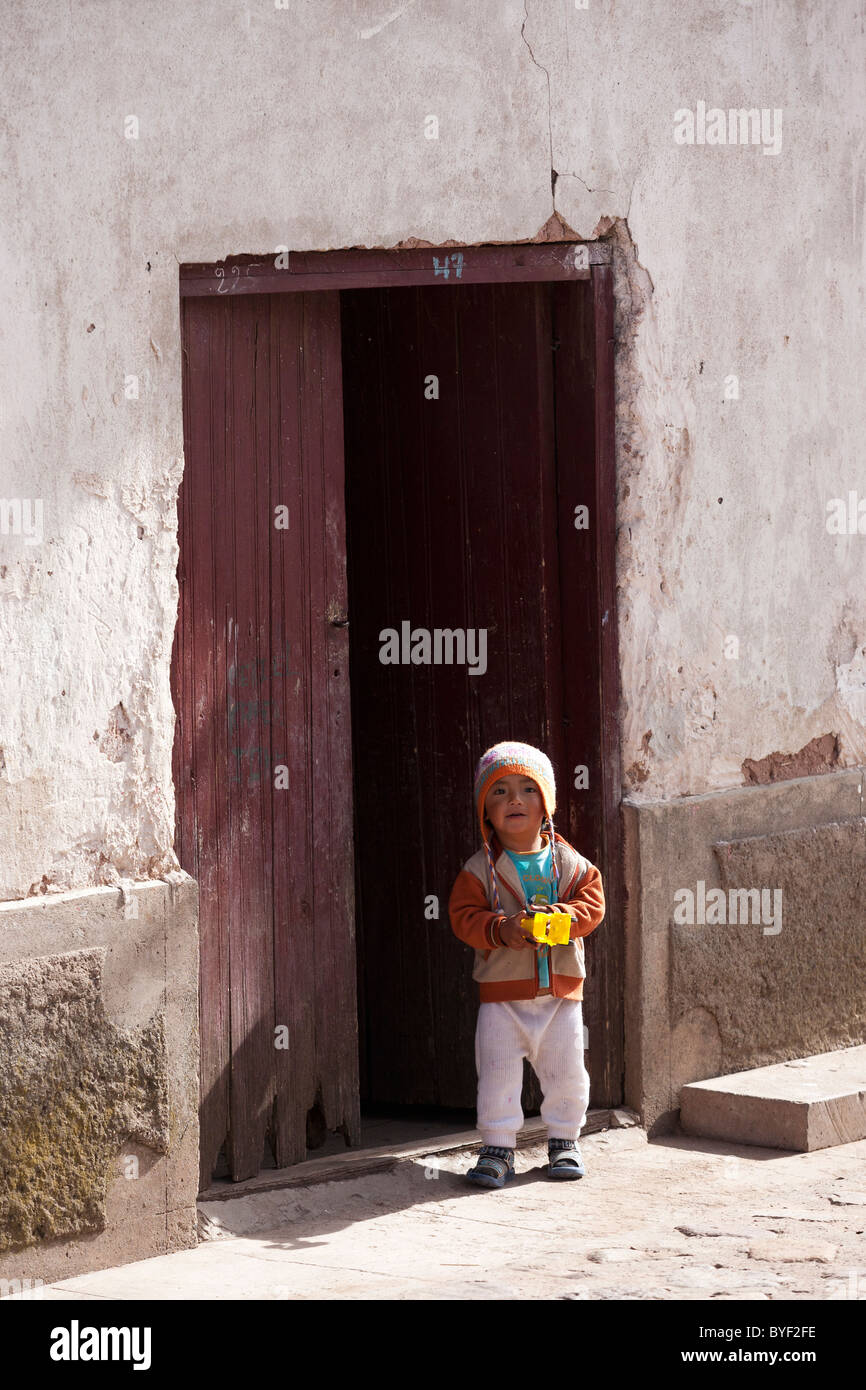 A young child stands in front of his home on the streets of Quinua ...