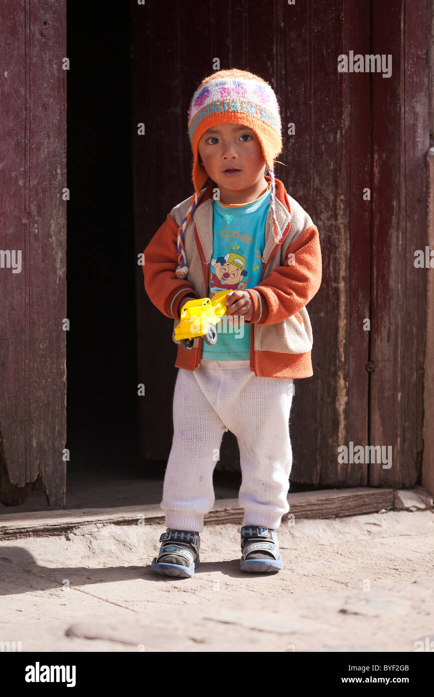 A young child stands in front of his home on the streets of Quinua ...