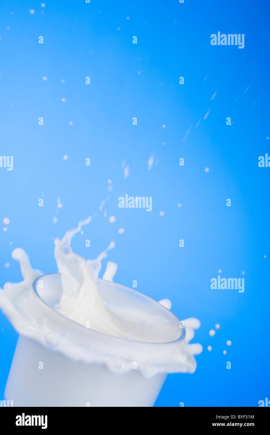 Splash of fresh cold milk over blue background Stock Photo - Alamy