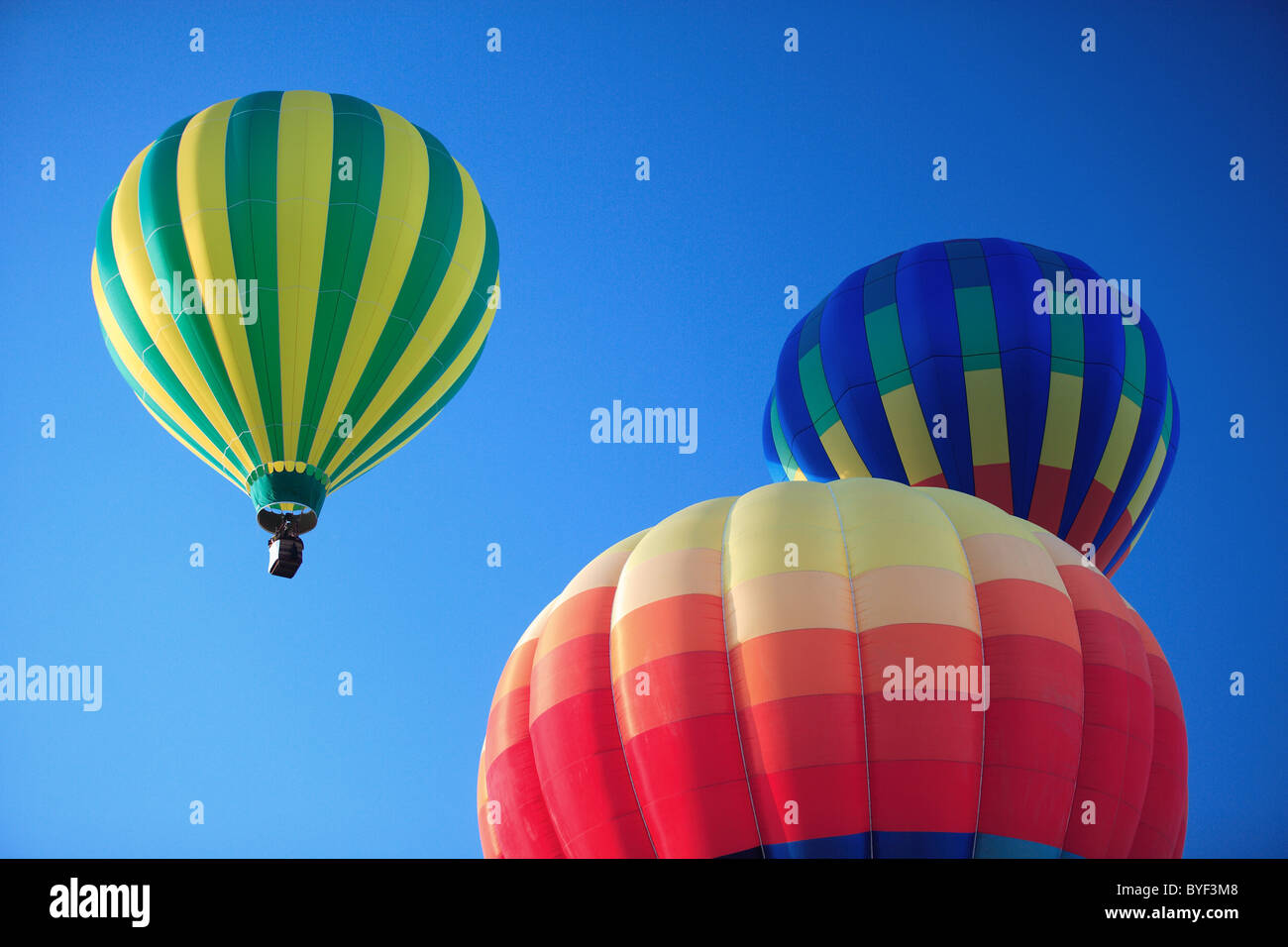 3 colorful hot air balloons floating lazily away on a vibrant blue sky ...