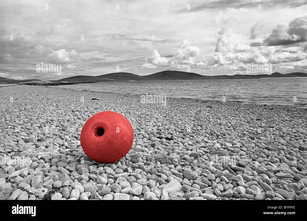 A metal fishing buoy on a shingle beach on the island of Berneray ...