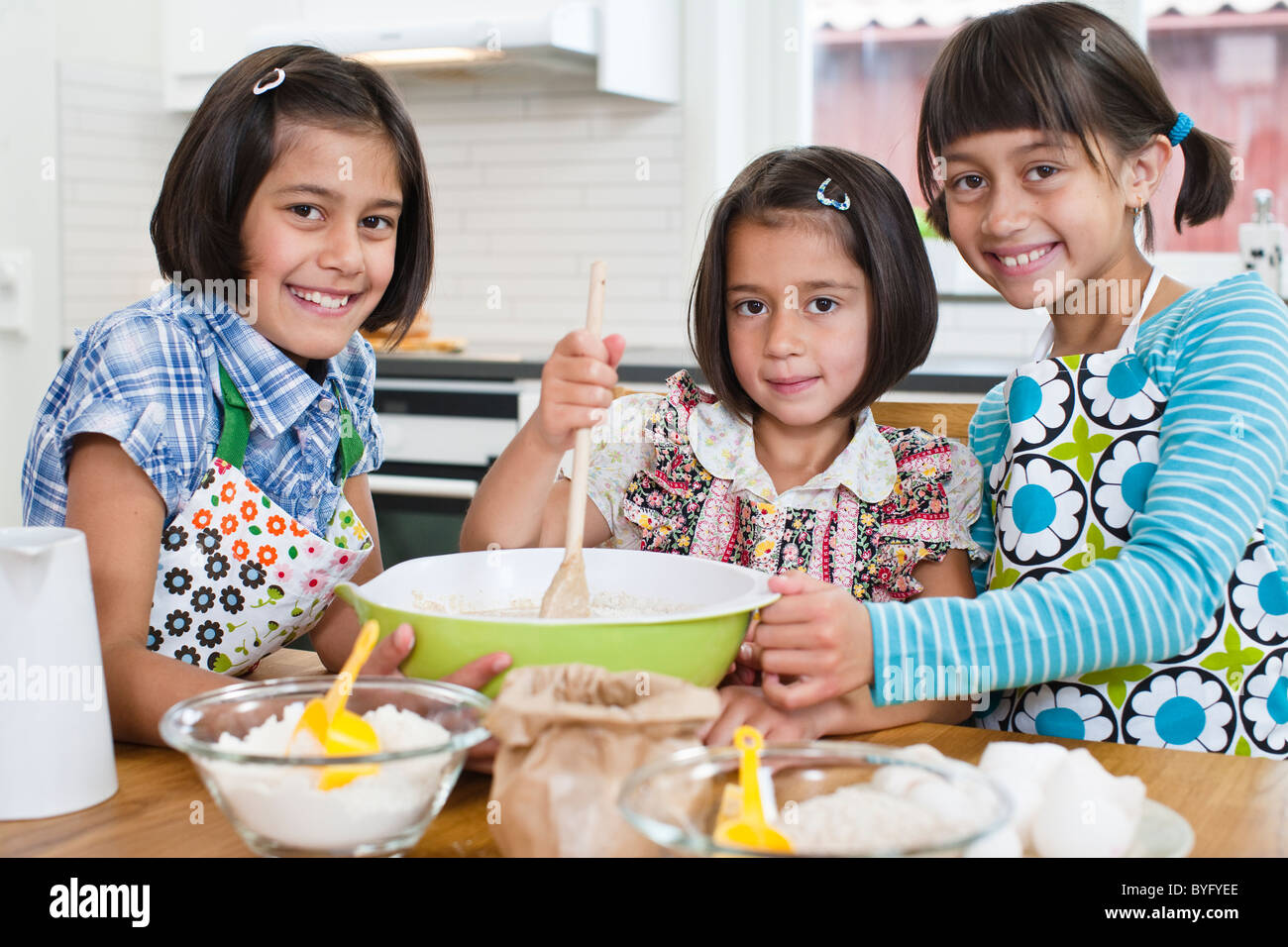 Portrait of three girls baking in kitchen Stock Photo - Alamy