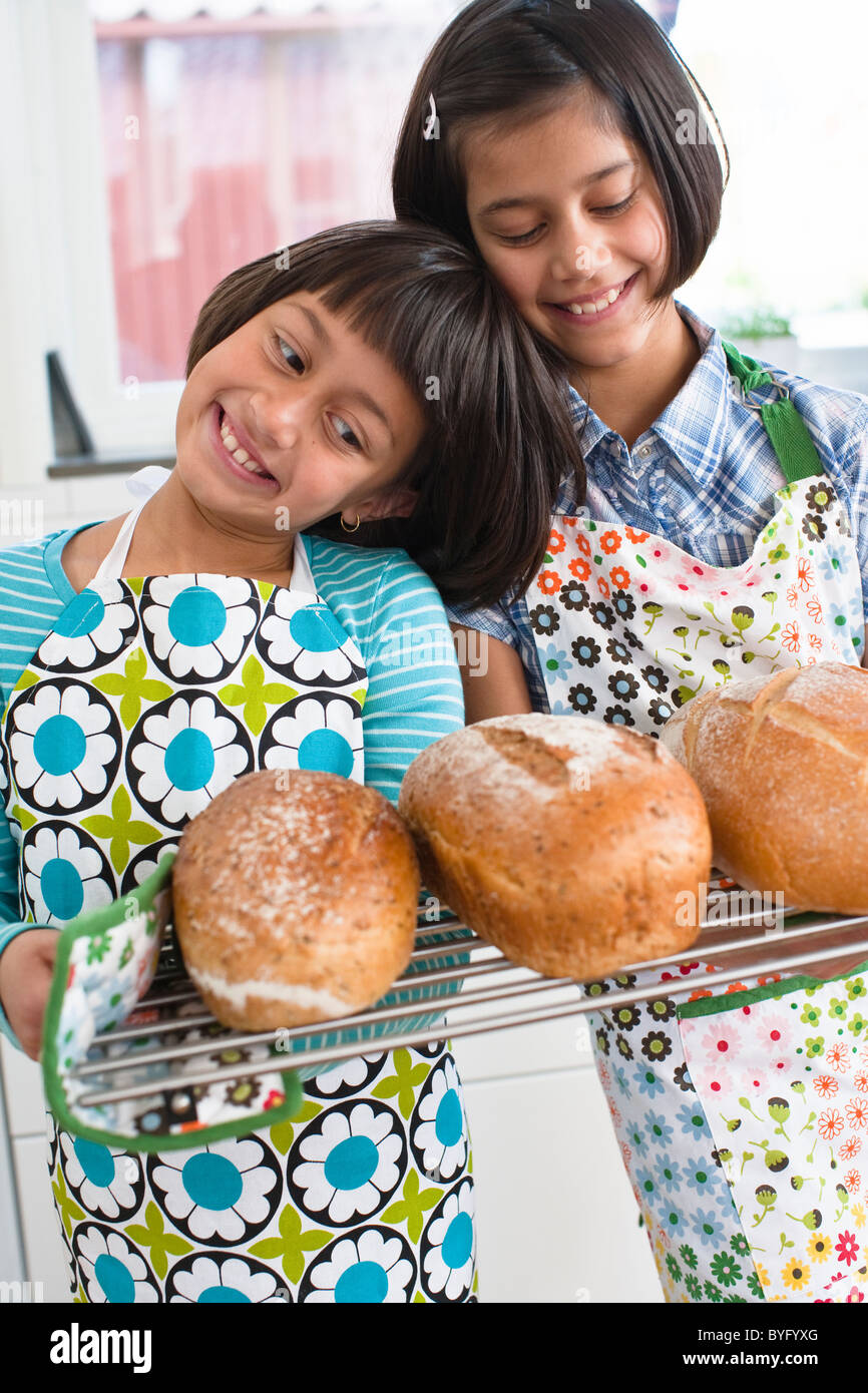 Two girls holding fresh bread in kitchen Stock Photo - Alamy