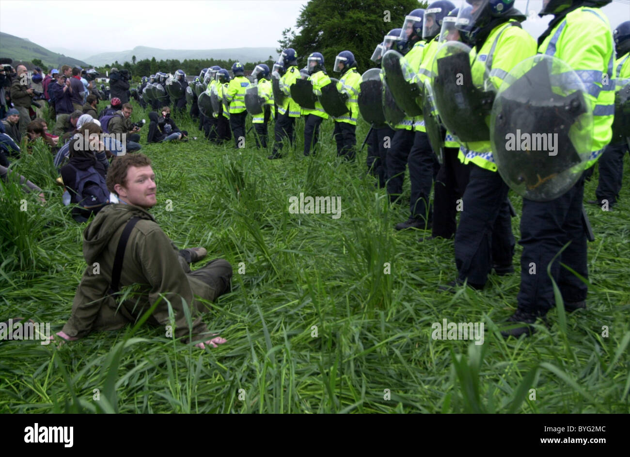 Protester sitting on the ground in a field at the in front of a line ...