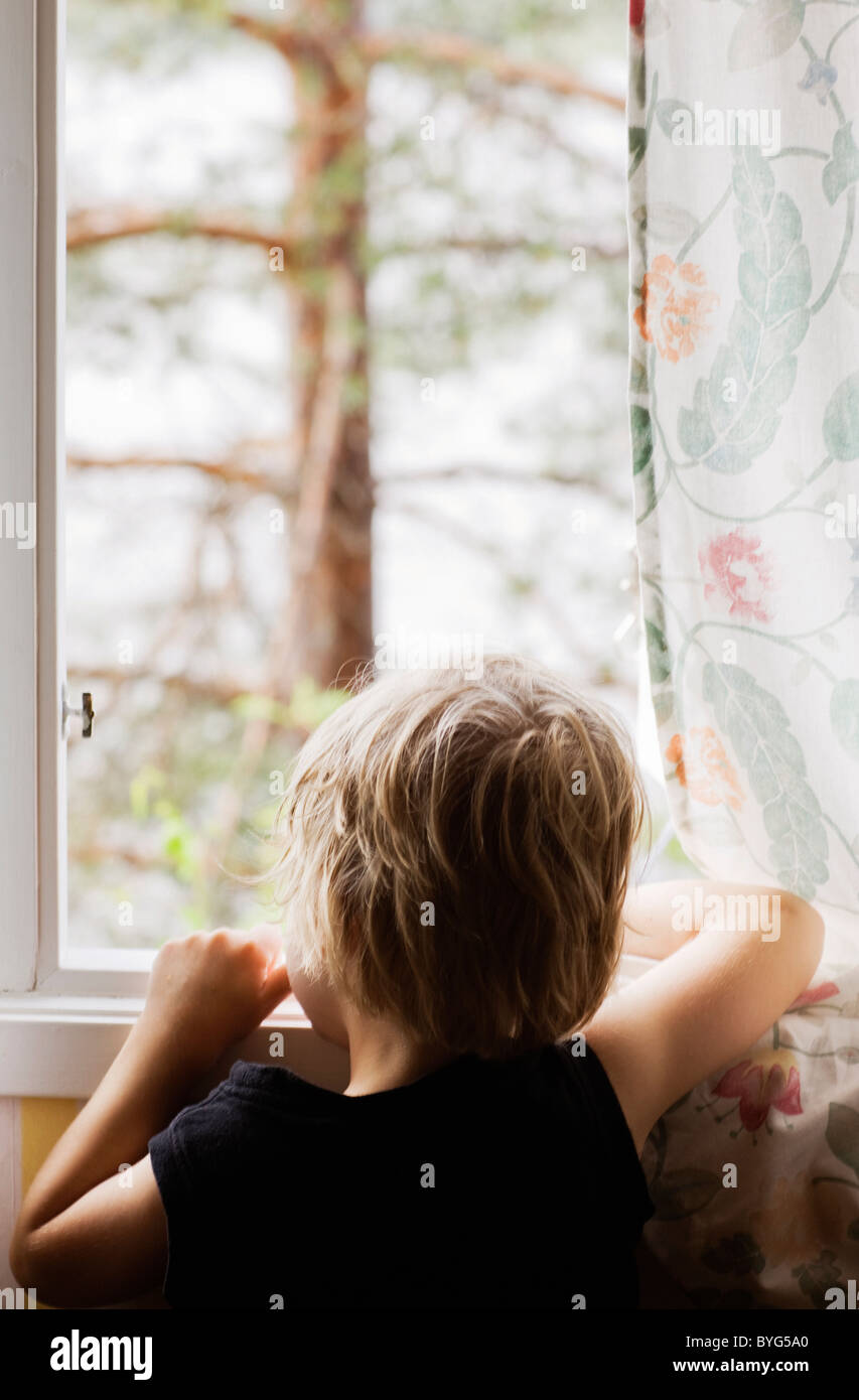 Boy looking through window Stock Photo - Alamy