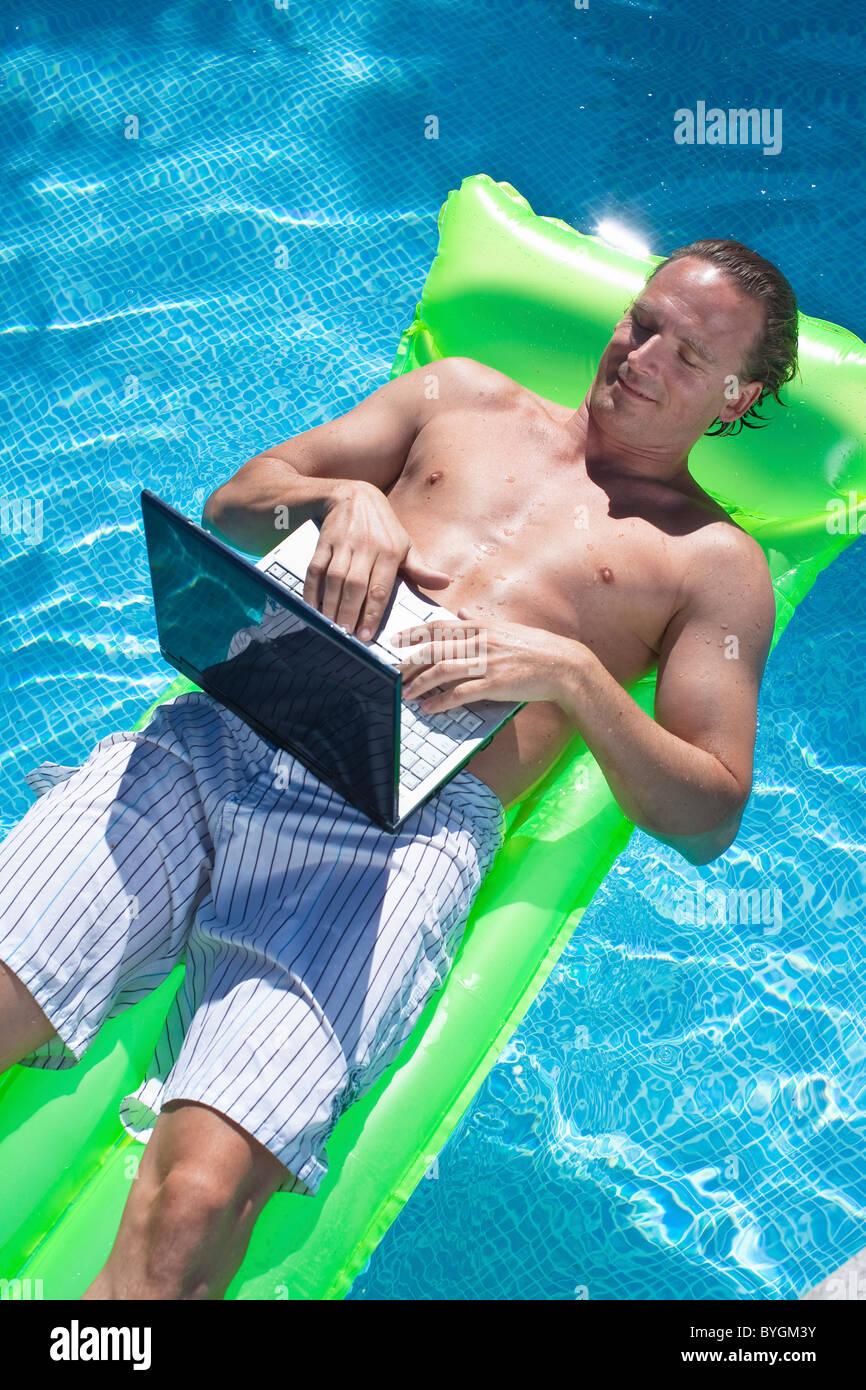 Man floating on inflatable raft and working on laptop Stock Photo - Alamy