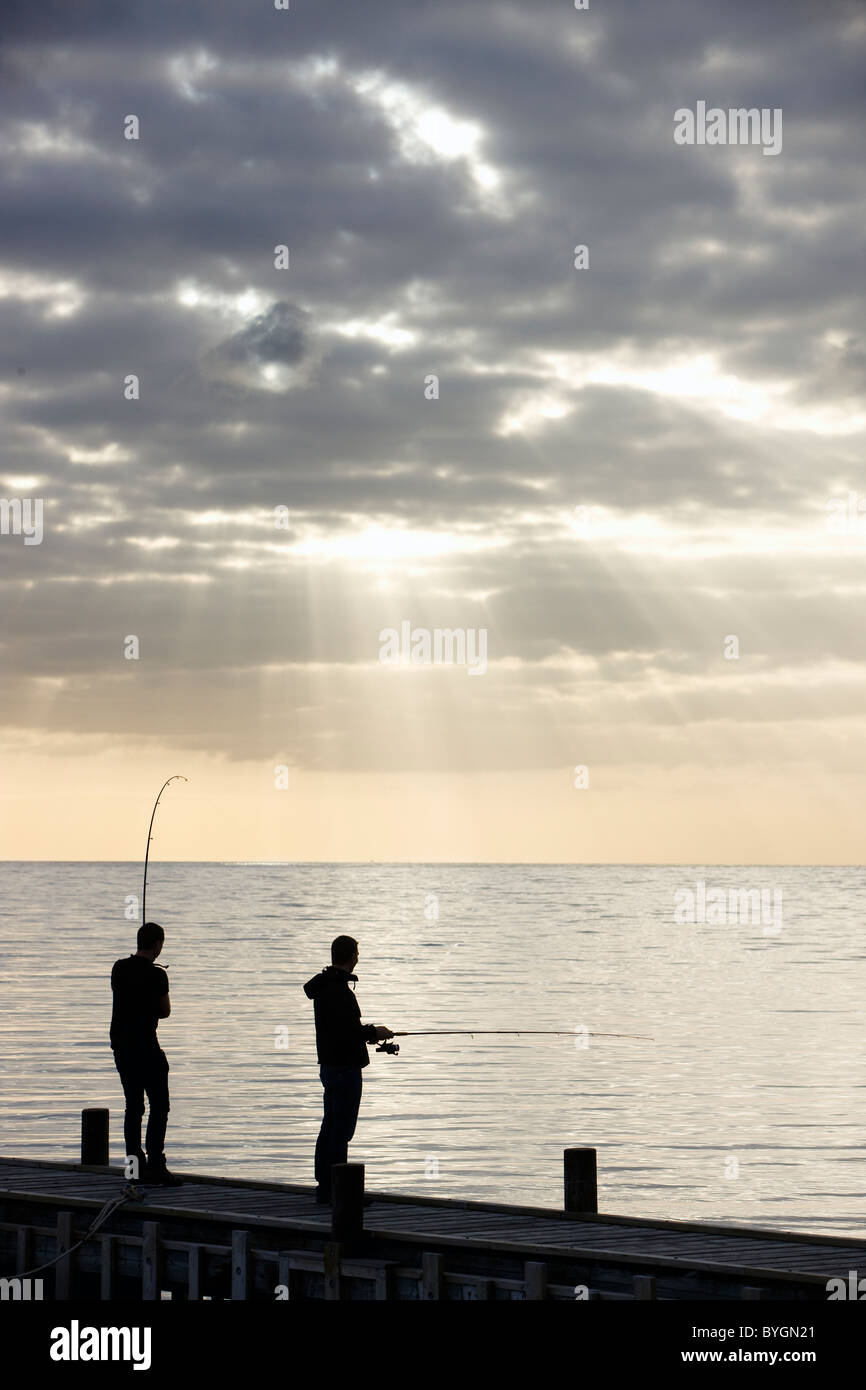 Two men fishing from jetty Stock Photo - Alamy