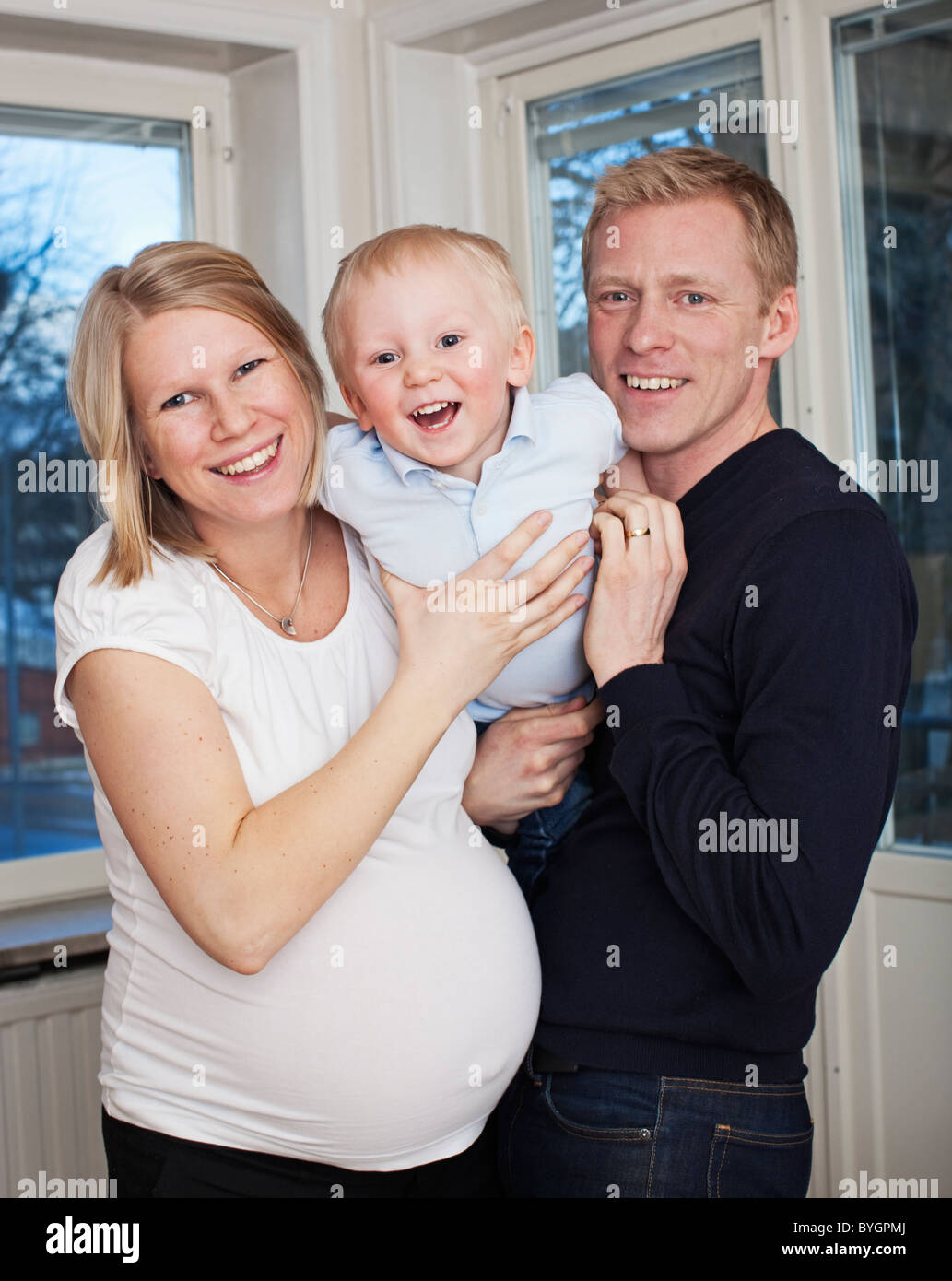Portrait of boy with parents by window Stock Photo - Alamy