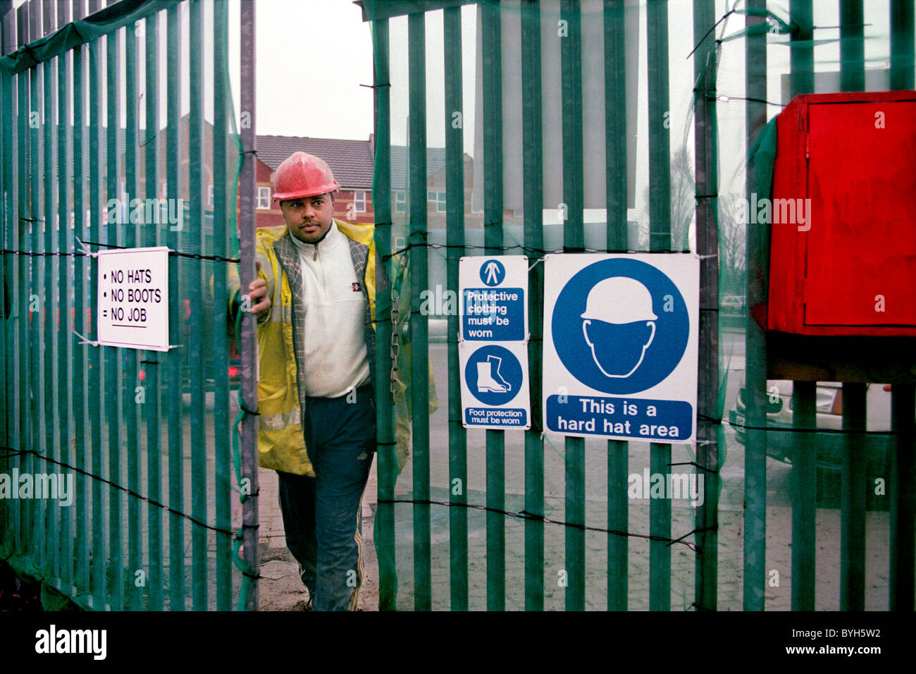 Asian worker at metal site gates showing safety signs Stock Photo - Alamy