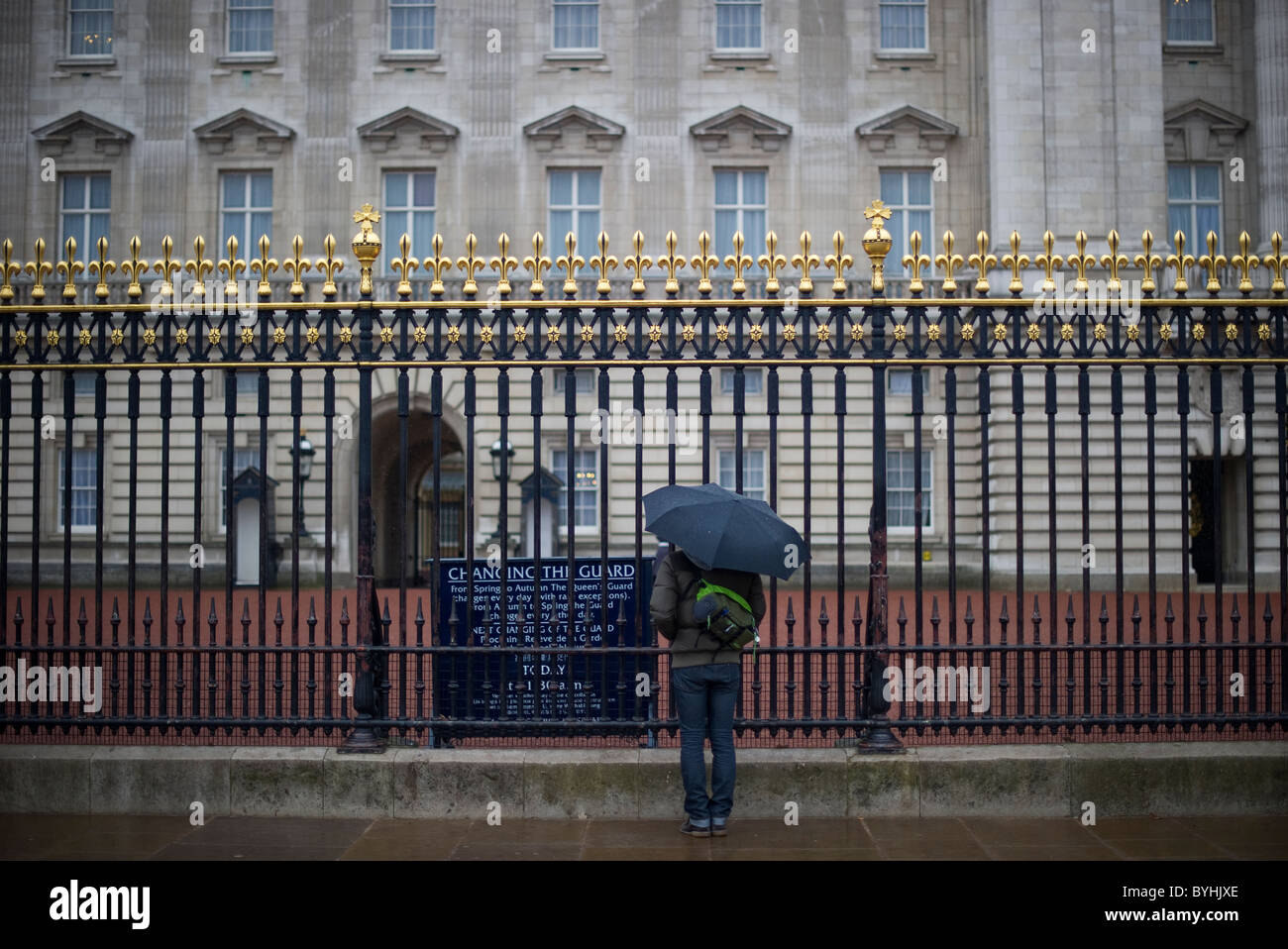 A man looks through the railings at Buckingham Palace in London Stock ...
