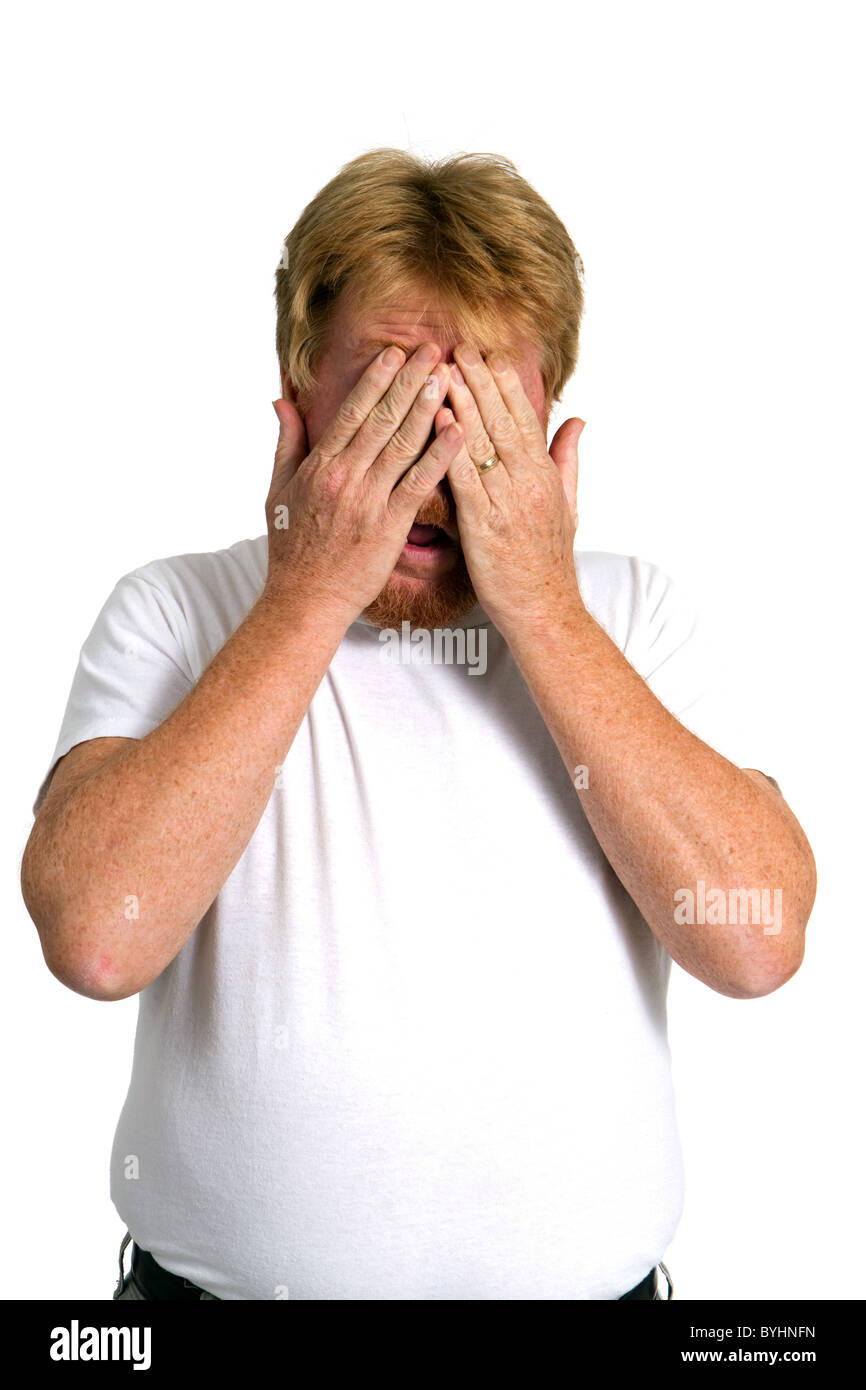 Man covers his eyes with his hands to shield himself from the sight ...