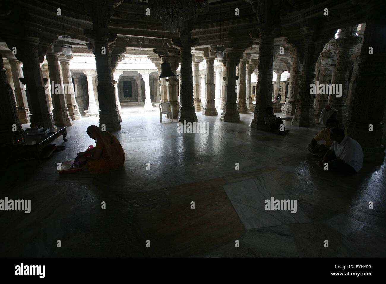Devotees seated in prayer inside Jain marble Adishwar Chaumukha Mandir ...