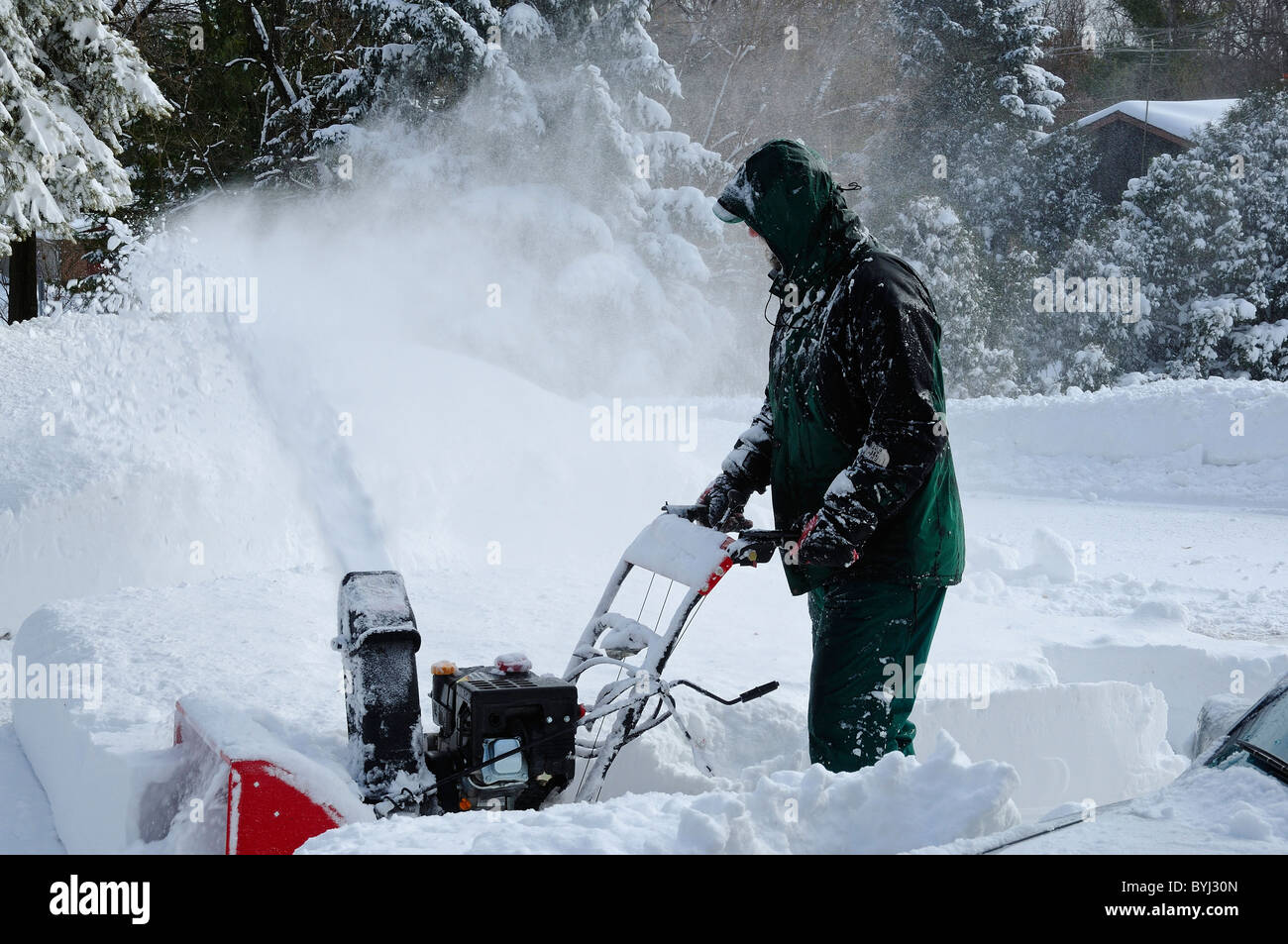 Man using snow blower to clear snow off driveway after blizzard Stock ...