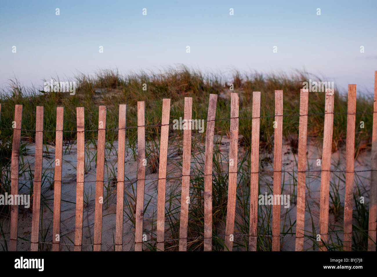 USA, Massachusetts, Barnstable, Fence along Cape Cod sand dunes at sunset on summer evening ...