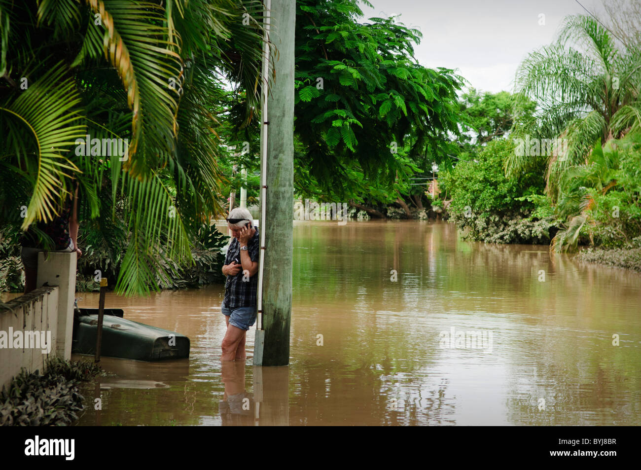 Man talking on his mobile phone while standing in flood waters in ...