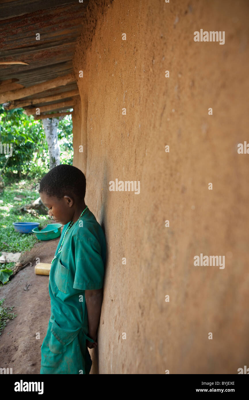 A young child stands alone outside her house in rural Masaka, Uganda ...