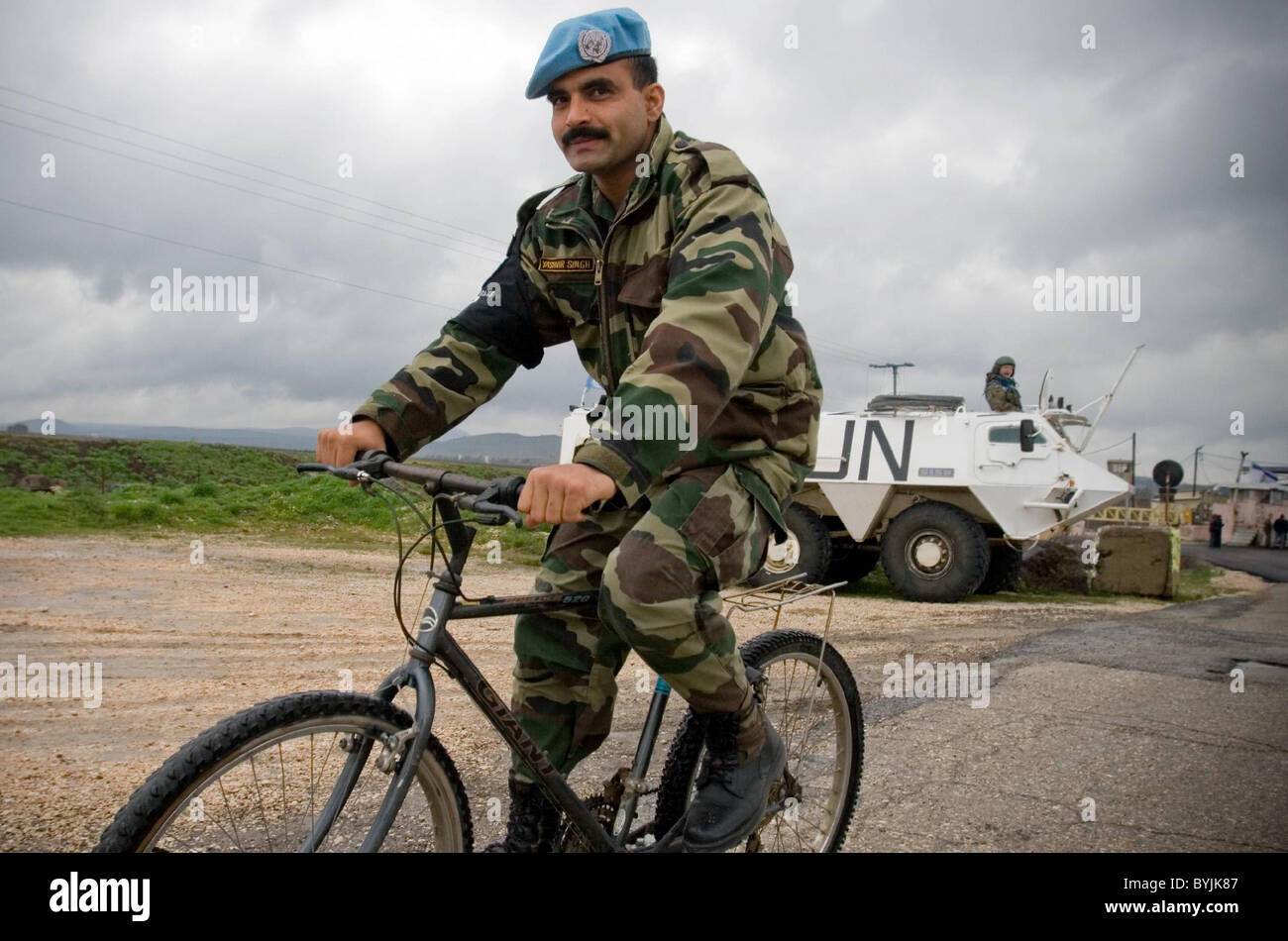 An UN Military Police officer riding an bicycle next to an UN armed ...