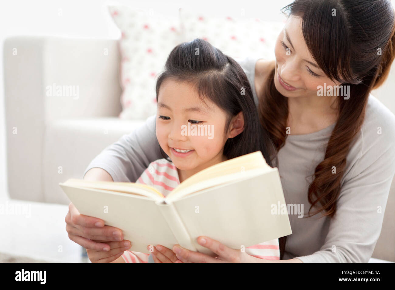 Mother and daughter reading a book together Stock Photo - Alamy