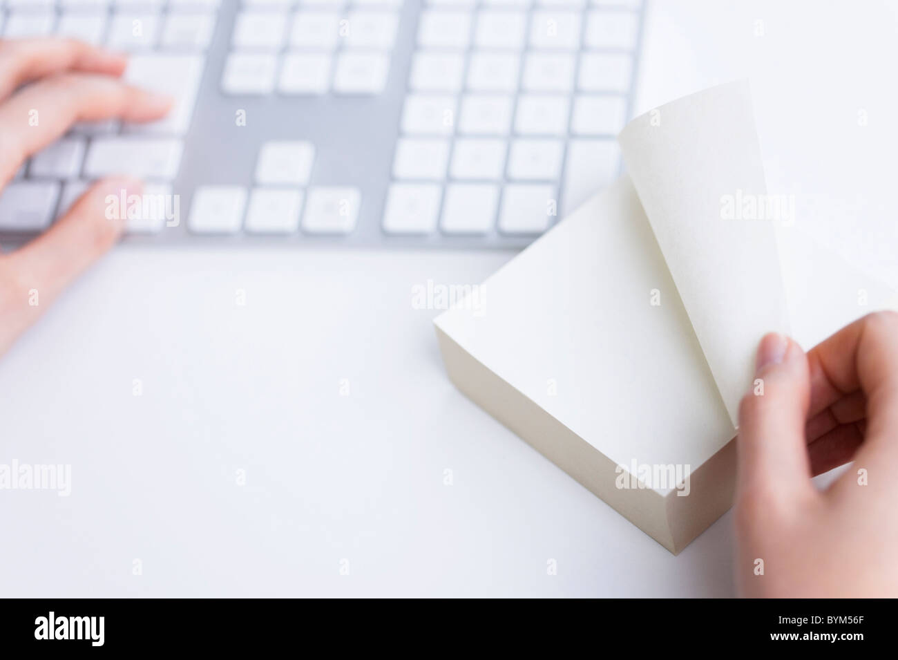 Hand typing and turning a page on a note pad Stock Photo - Alamy