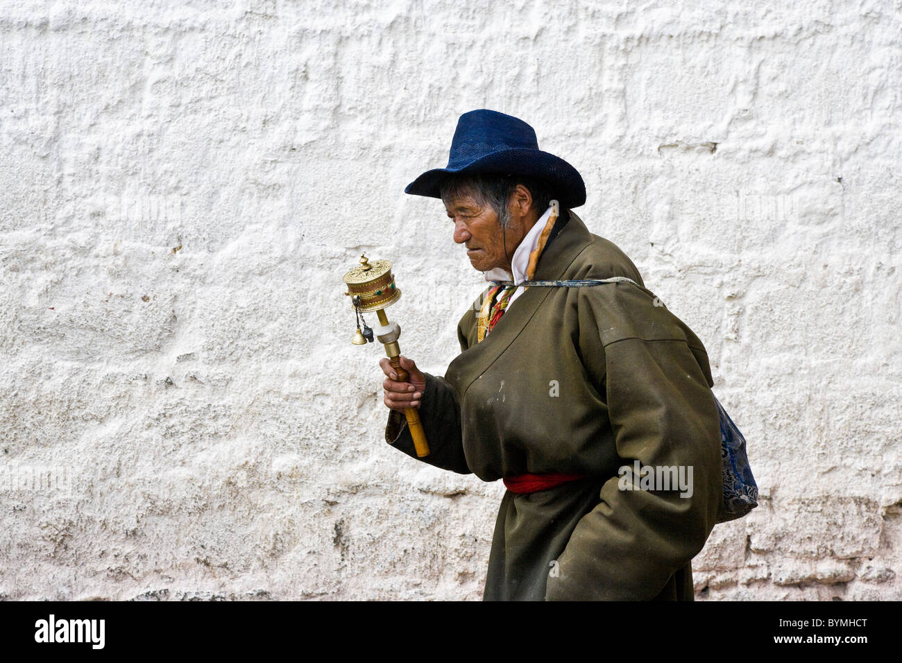 Tibetan man pilgrim with prayer wheel outside the walls of the Jokhang ...
