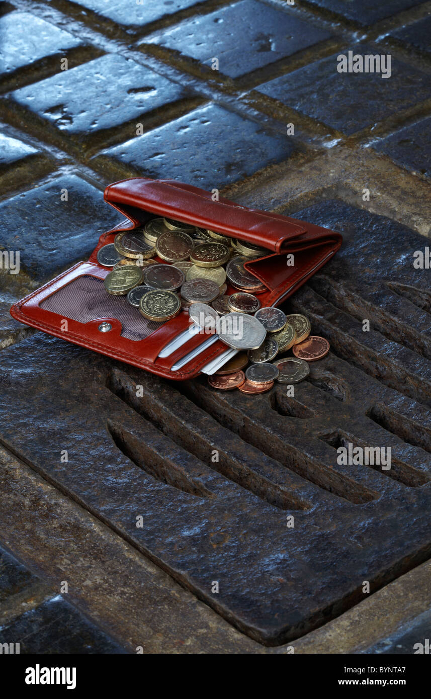 Purse of Money Falling down Drain Stock Photo - Alamy
