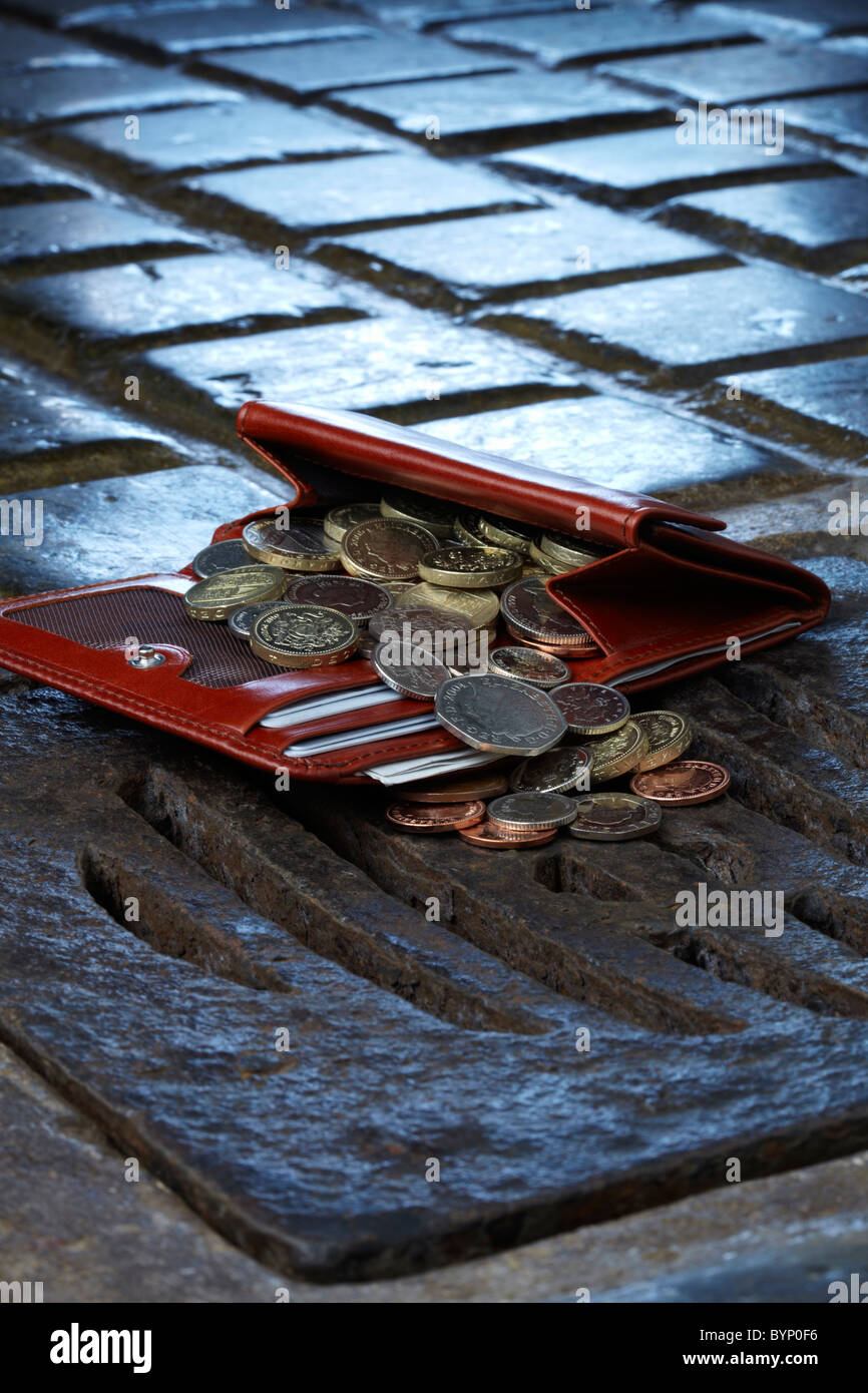 Purse of Money Falling down Drain Stock Photo - Alamy