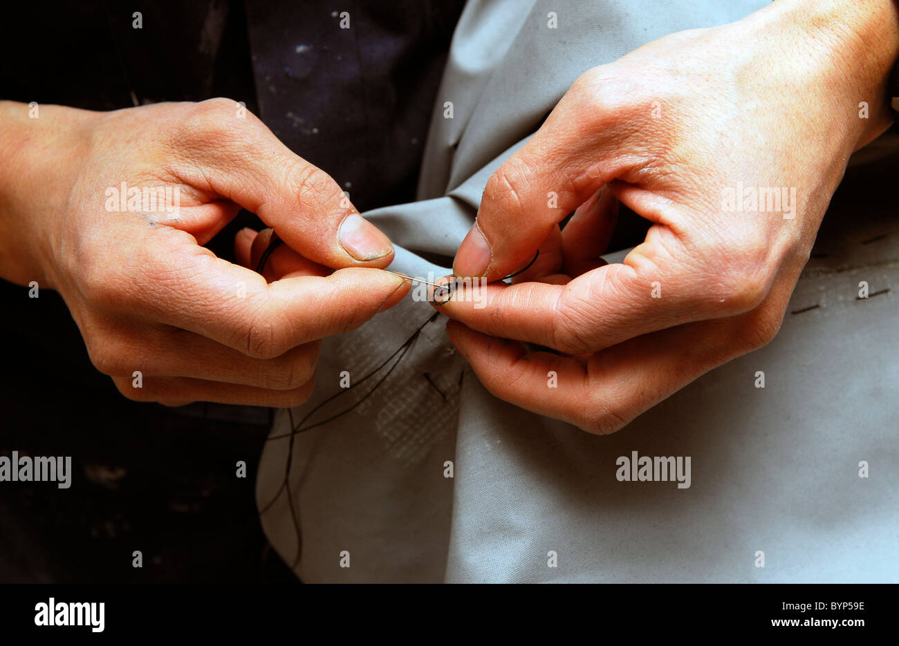 Man threading a needle in textile workshop, Bristol, UK Stock Photo - Alamy