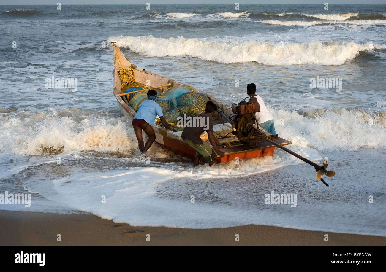 Fisherman launch a fishing boat into the surf from the beach of ...