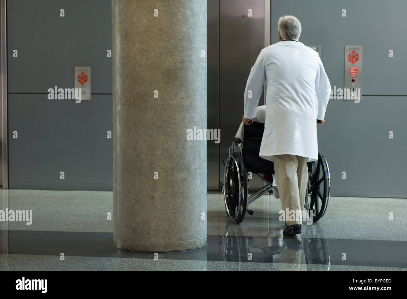 Doctor pushing patient in wheelchair toward elevator Stock Photo - Alamy