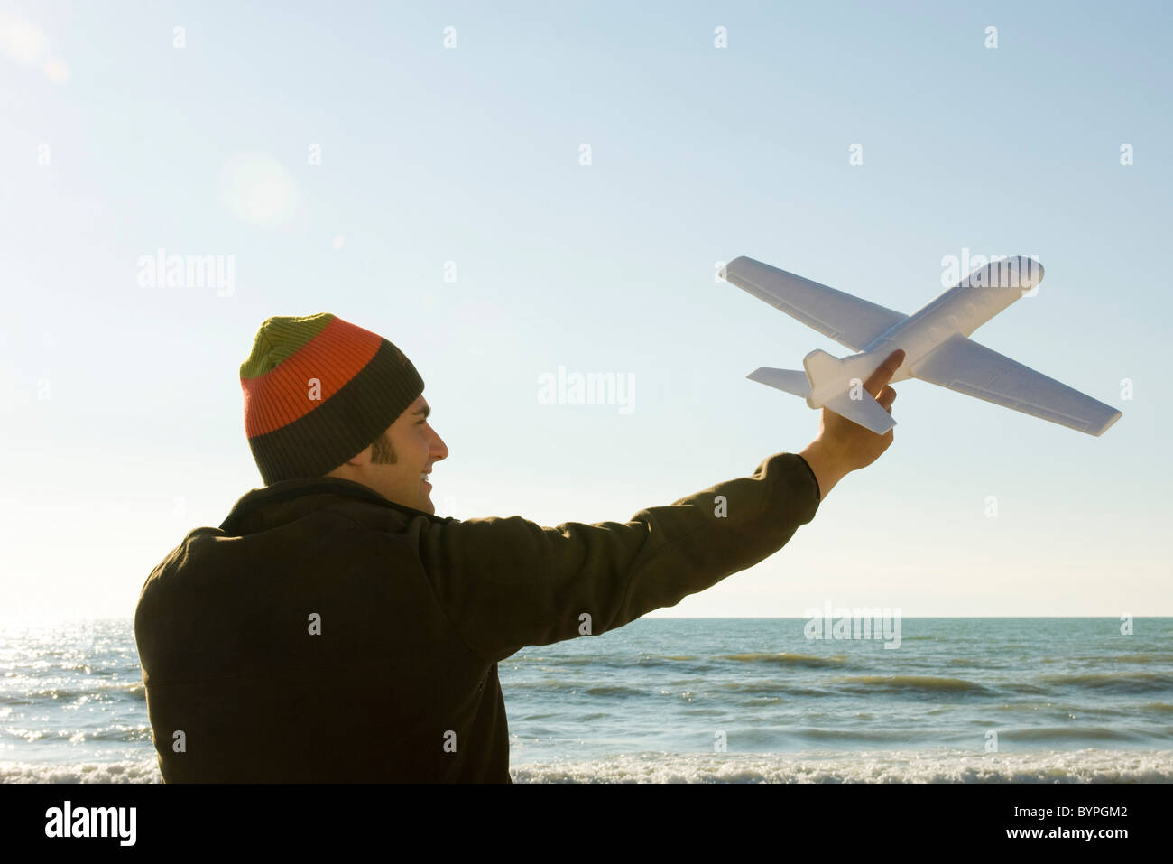 Young man at beach holding aloft toy airplane Stock Photo - Alamy