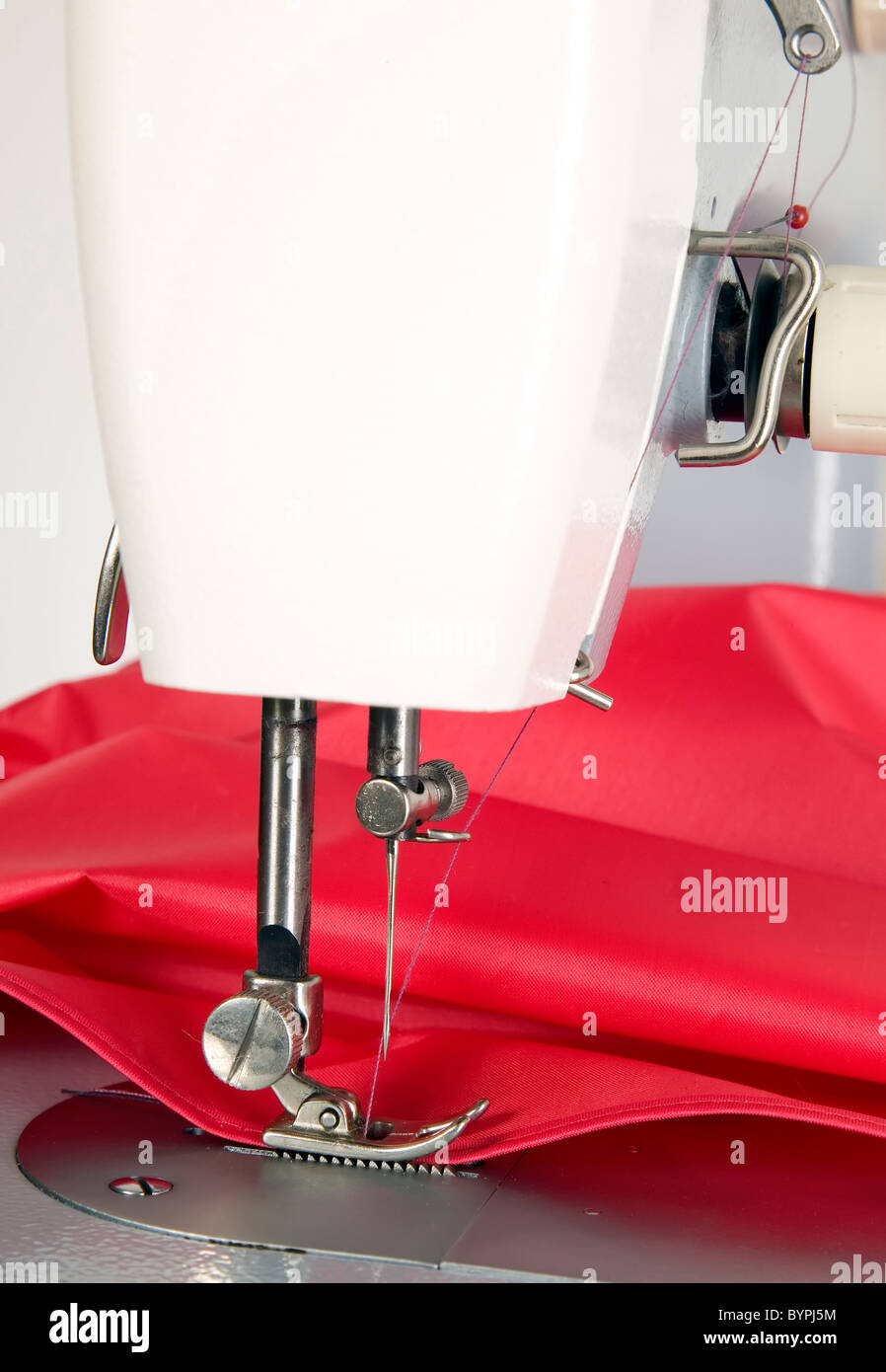 Sewing machine is stitching piece of red fabric Stock Photo - Alamy