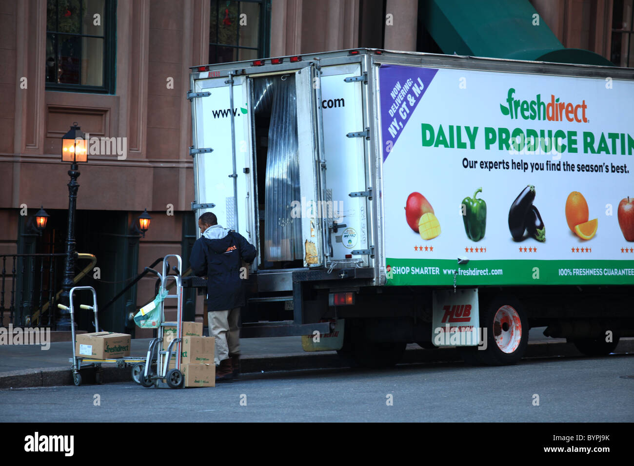 Man unloading boxes from the back of a delivery truck in early morning ...