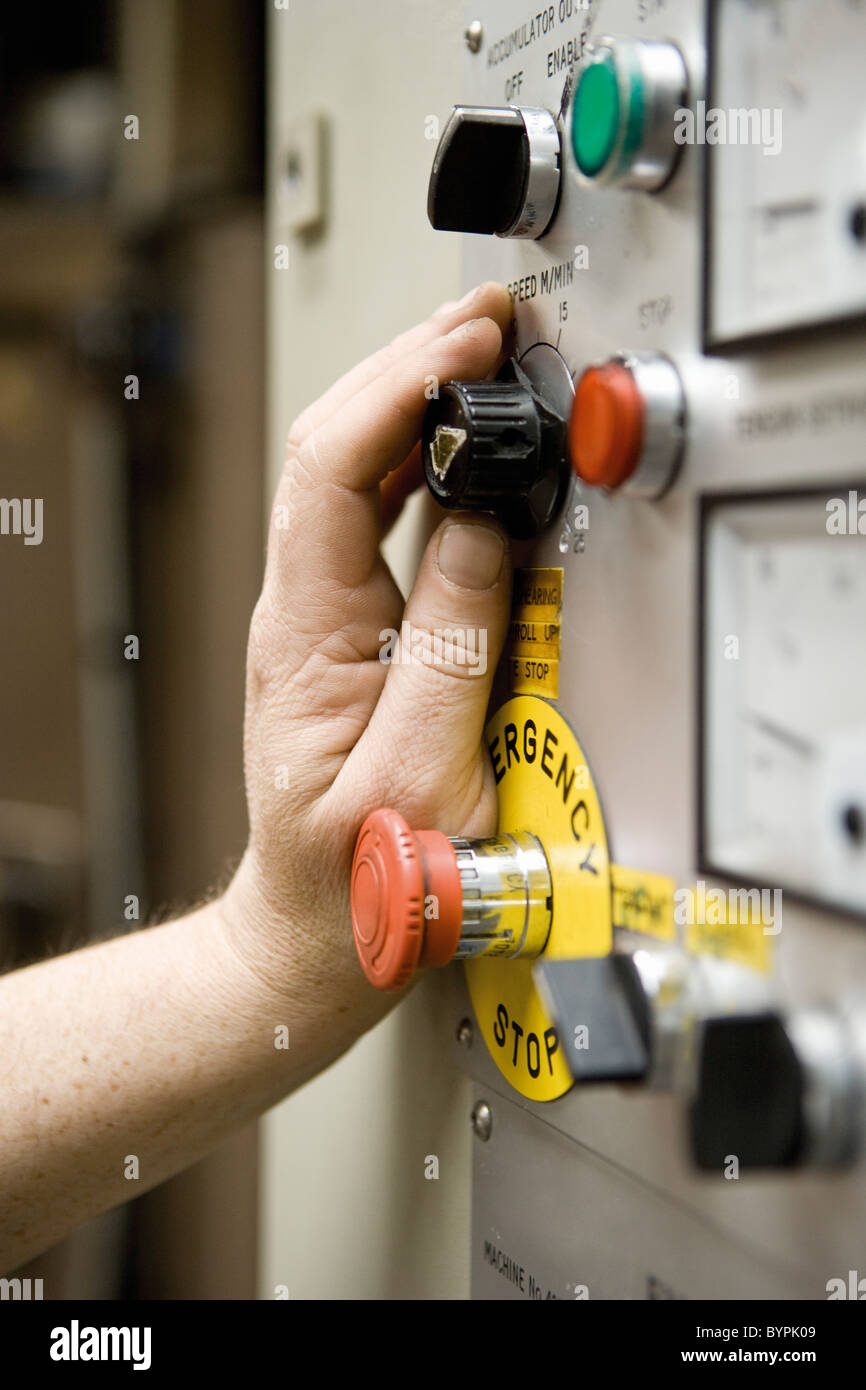 Worker adjusting speed knob on shearing machine control panel in carpet ...
