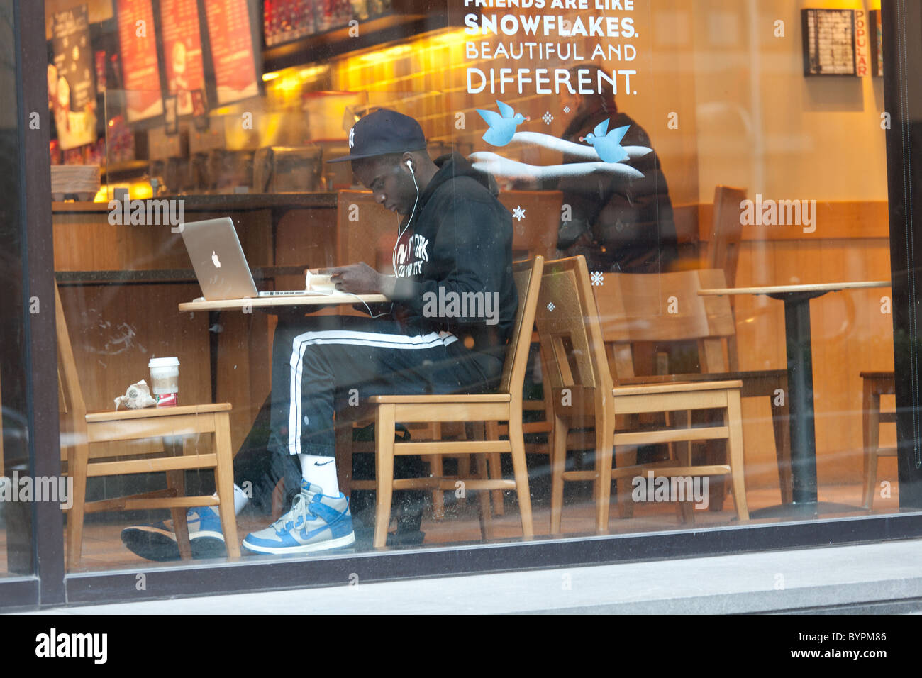 Young black man listening to music from this Apple MacBook computer in ...