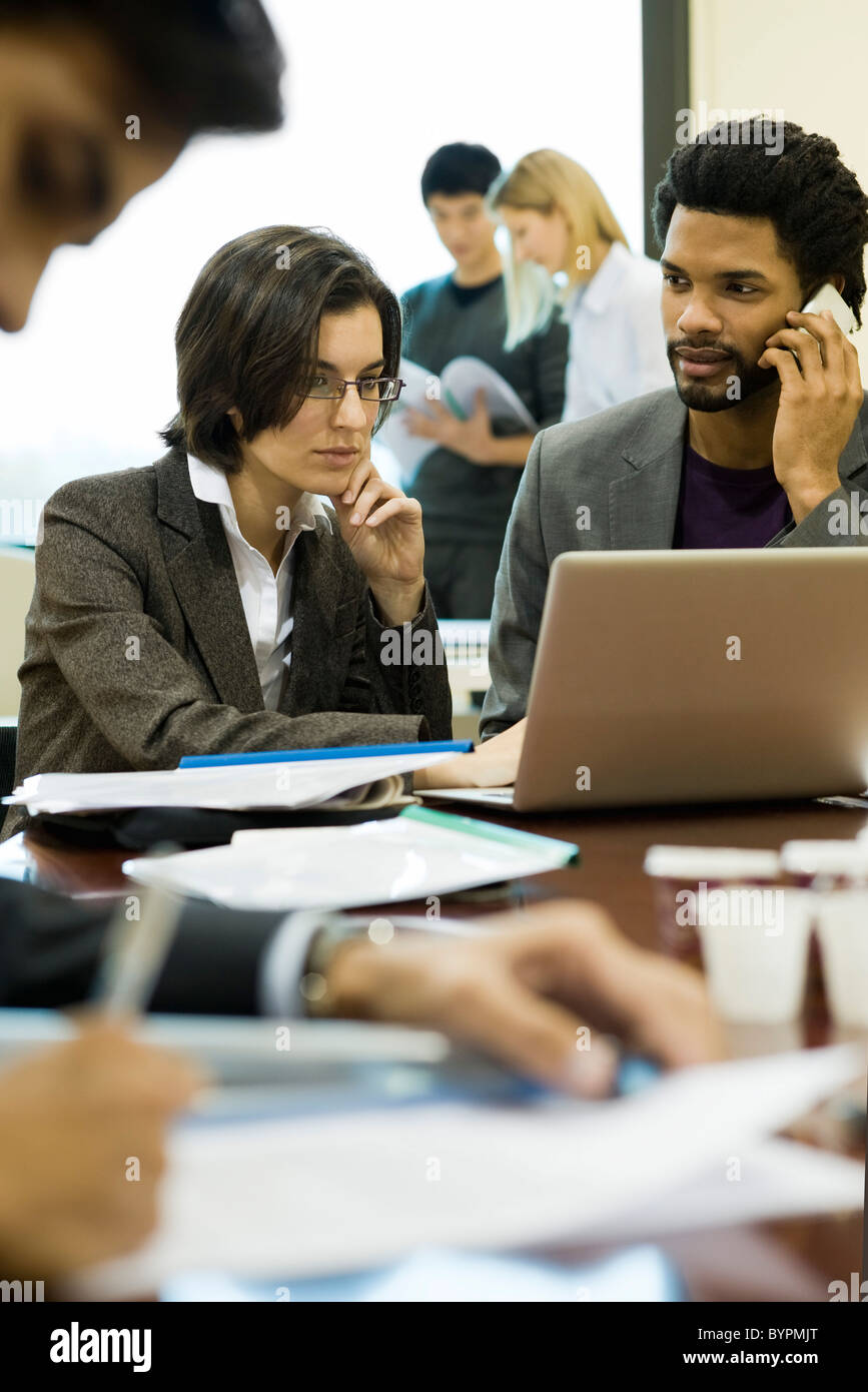 Executives working together, one using cell phone Stock Photo - Alamy