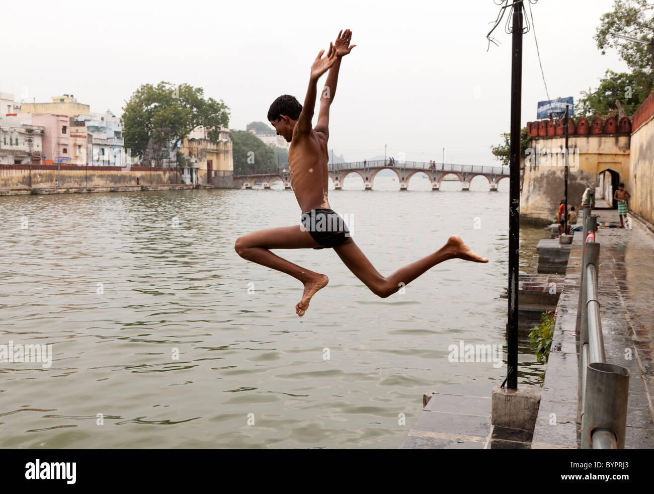 India, Rajasthan, Udaipur young boy leaping into Lake Pichola to wash ...