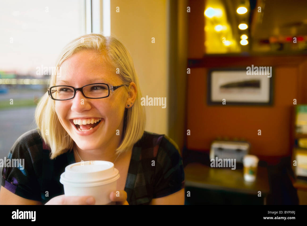a young woman smiling with coffee at a cafe Stock Photo - Alamy