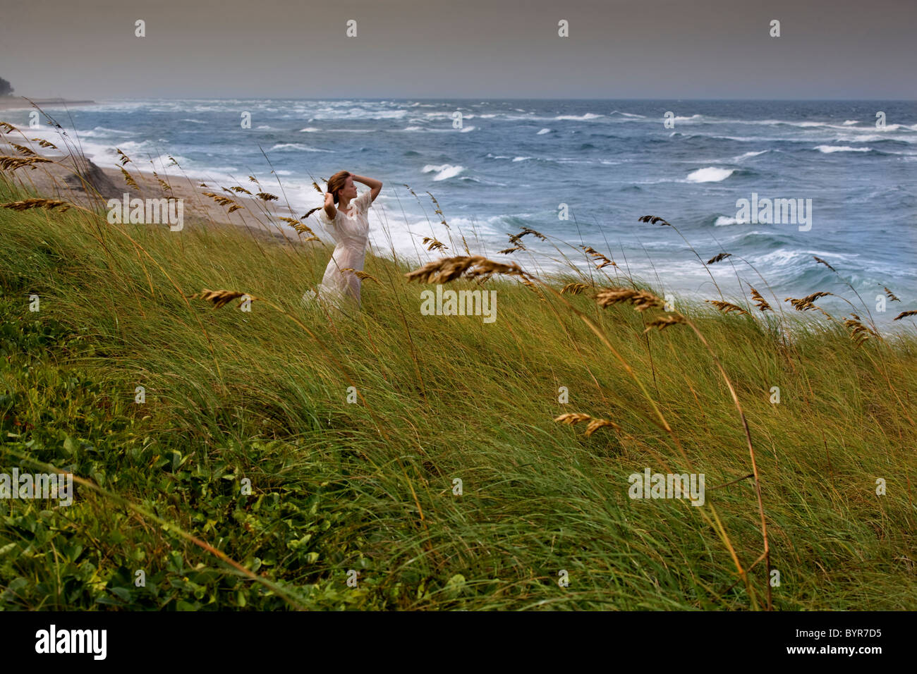 Young woman standing on beach on windy day Stock Photo - Alamy