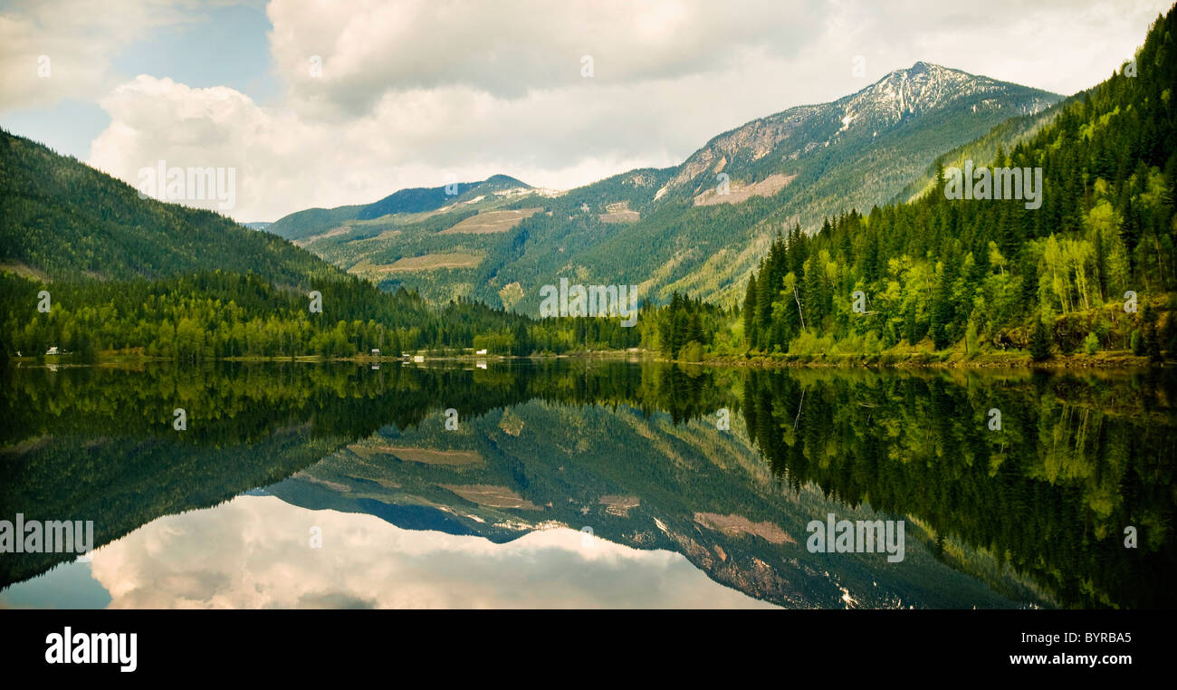 mountains reflected in a tranquil lake; golden british columbia, canada ...
