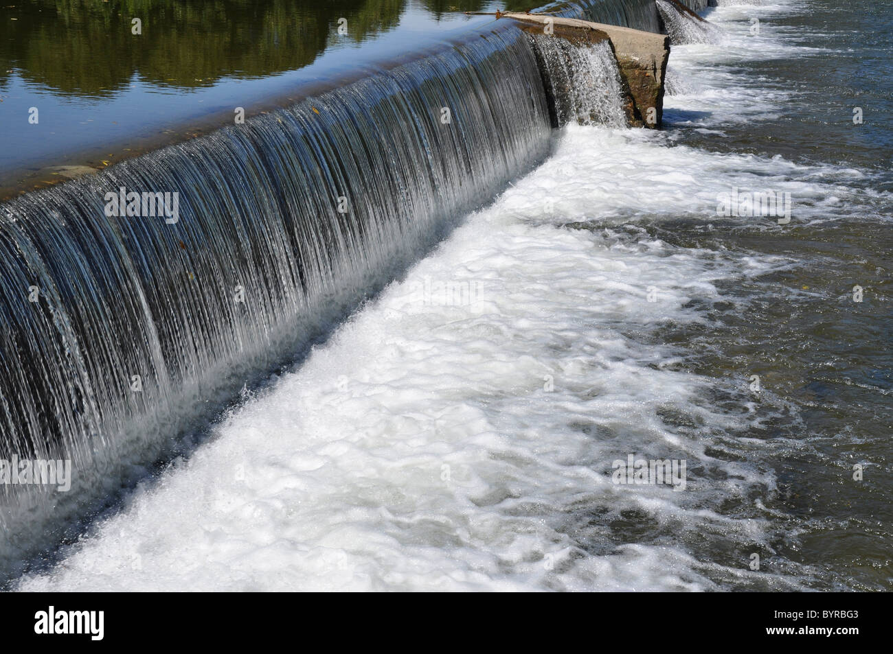 Foaming water coming over a small waterfall from a dam Stock Photo - Alamy