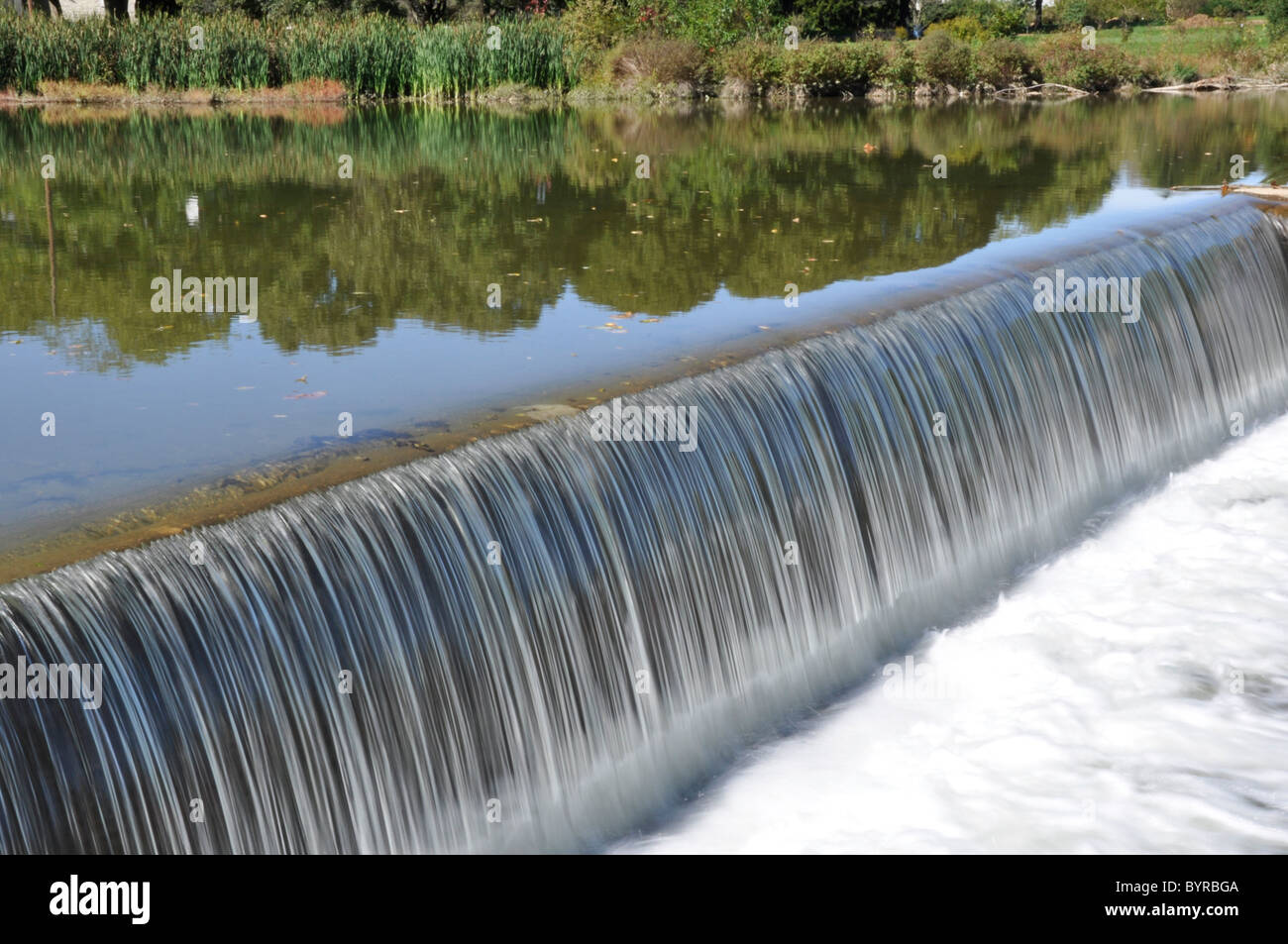 Foaming water coming over a small waterfall from a dam Stock Photo - Alamy