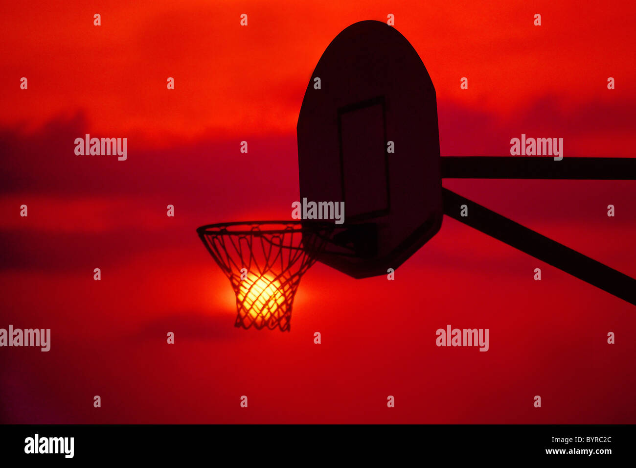 The sun sets behind basketball hoop. Symbolic of "acheiving goals Stock ...